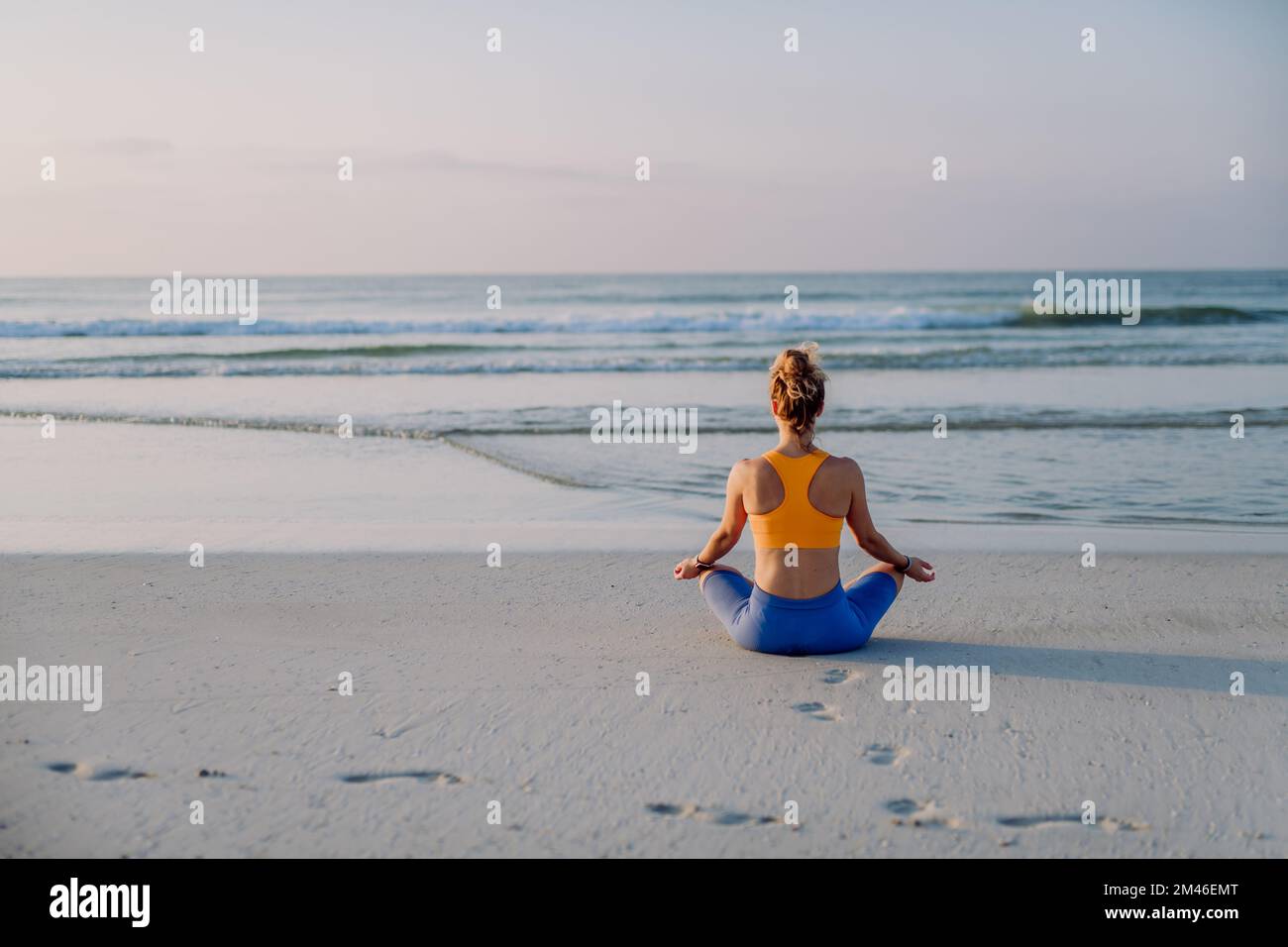 Rear view of young woman taking exercises at beach, morning routine and ...