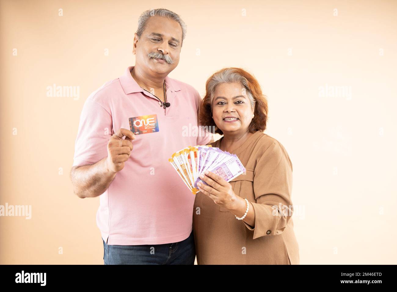 Happy senior Indian couple holding money and blank debit credit card in ...