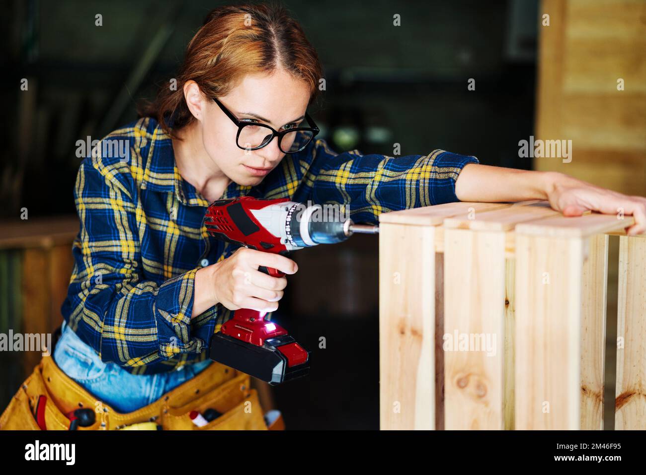 Woman in glasses using drill in workshop Stock Photo - Alamy