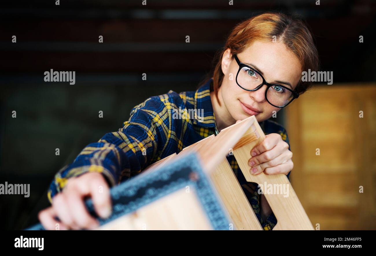 Young woman wearing glasses measuring wooden object using angle rulet ...