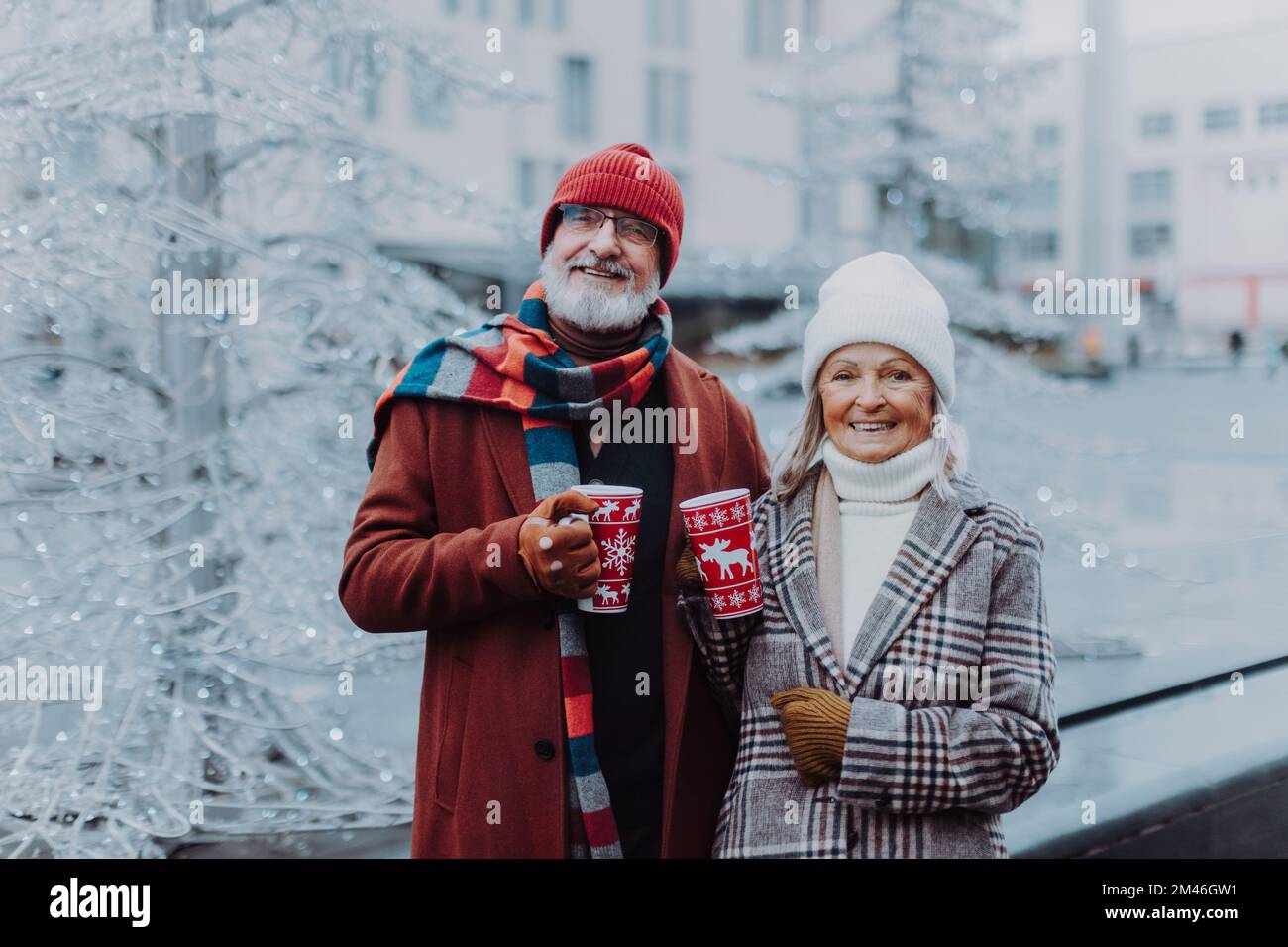 Happy senior couple enjoying christmas market, drinking muled wine ...