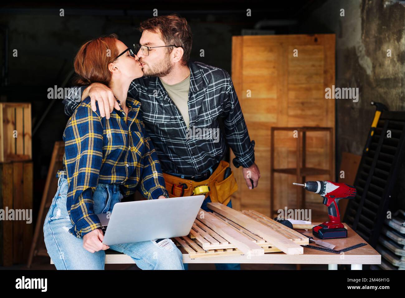 Young adult couple kissing celebrating success of their small business ...