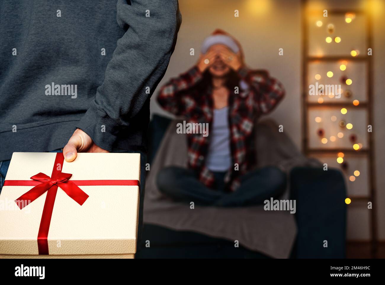 Christmas present boxes in hand behind back defocused woman with closed ...