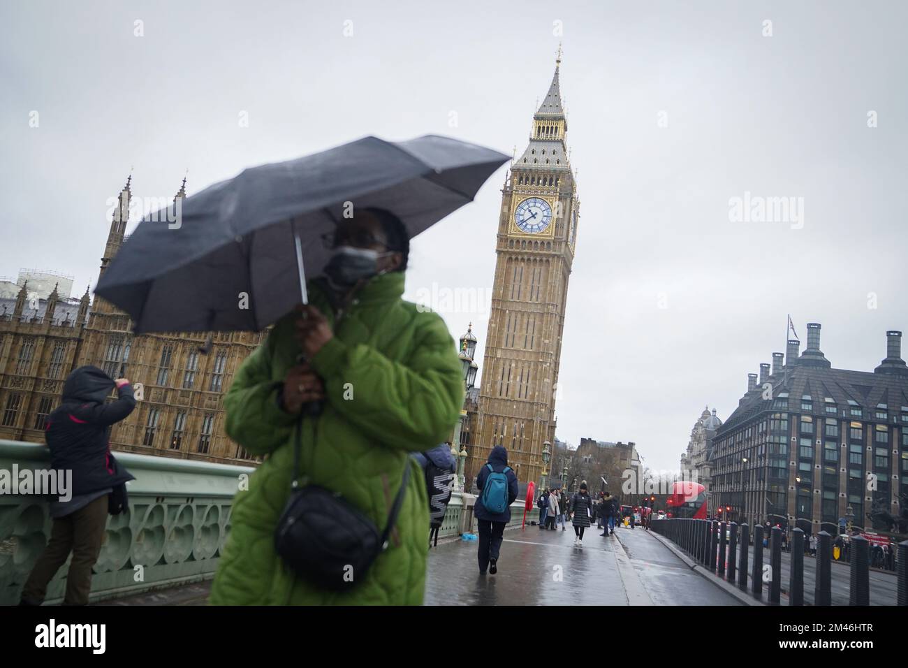 A woman shelters beneath an umbrella as she walks in the rain along ...