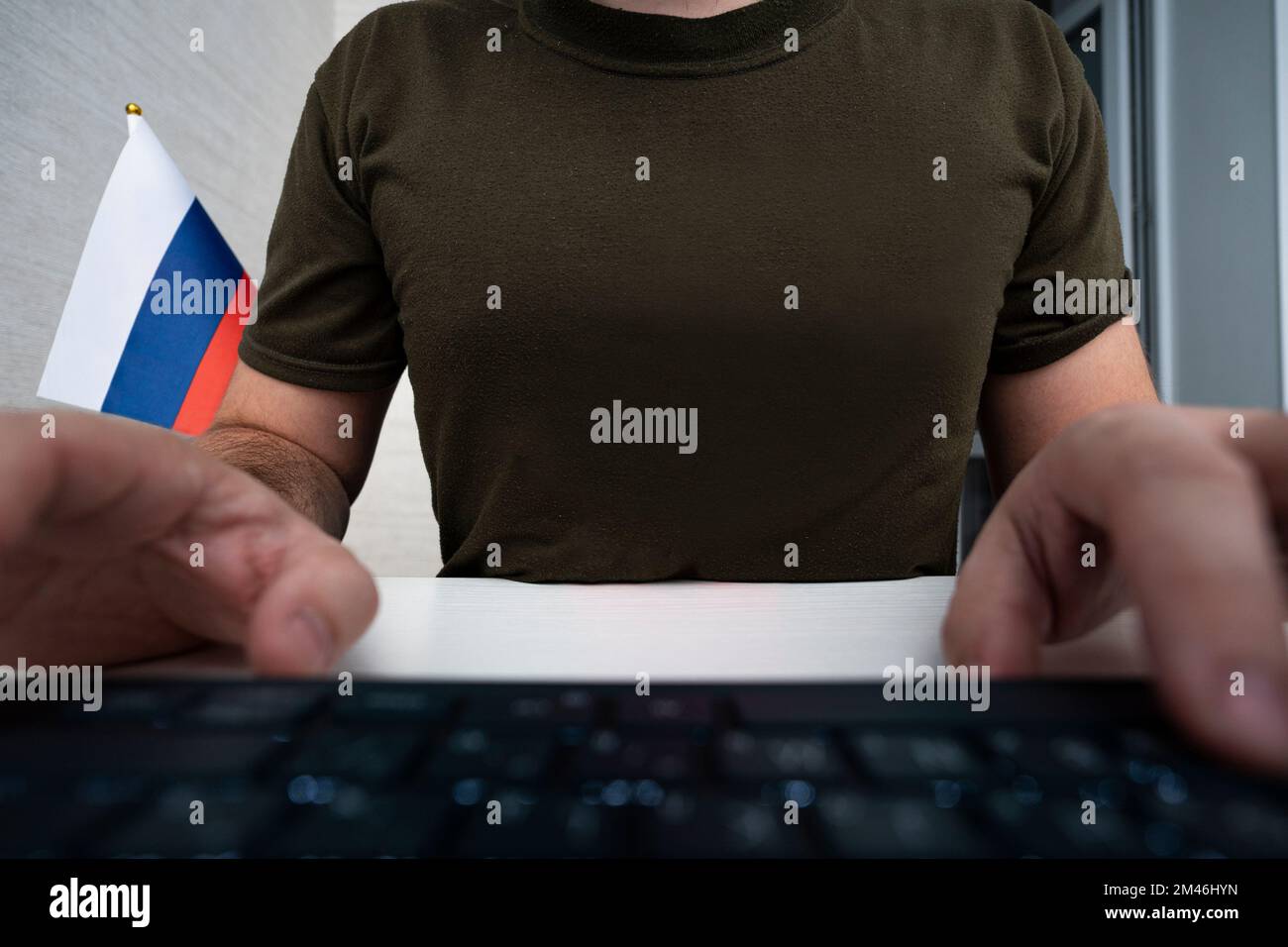 a male soldier in a military uniform is sitting at a computer. center ...
