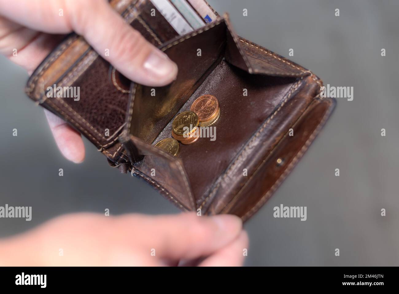 Man holding a wallet with a few coins in his hand Stock Photo - Alamy