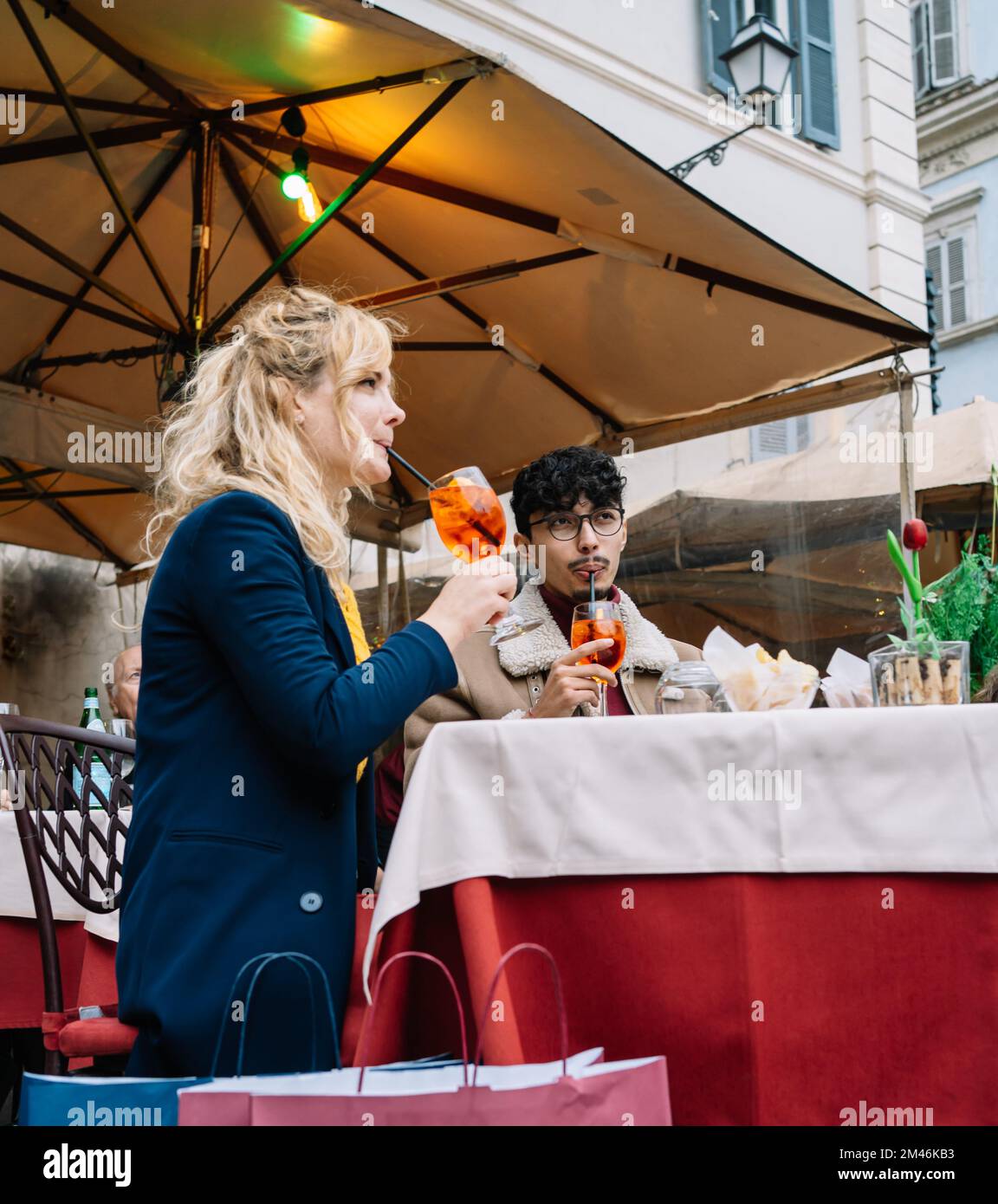 Young multi-ethnic engaged couple having drinks on a sunny fall/winter ...