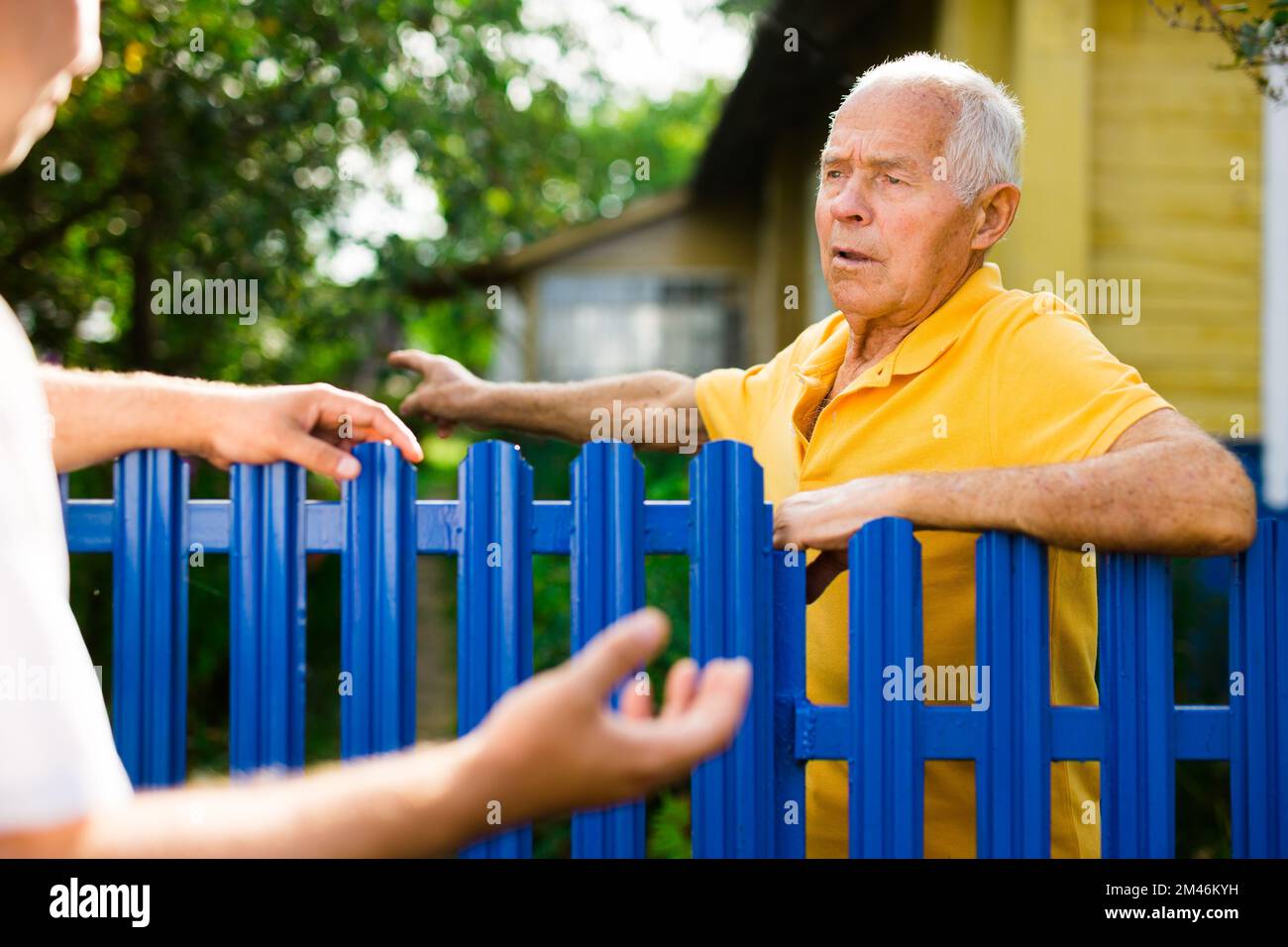 Elderly man discussing with neighbour beside house Stock Photo - Alamy