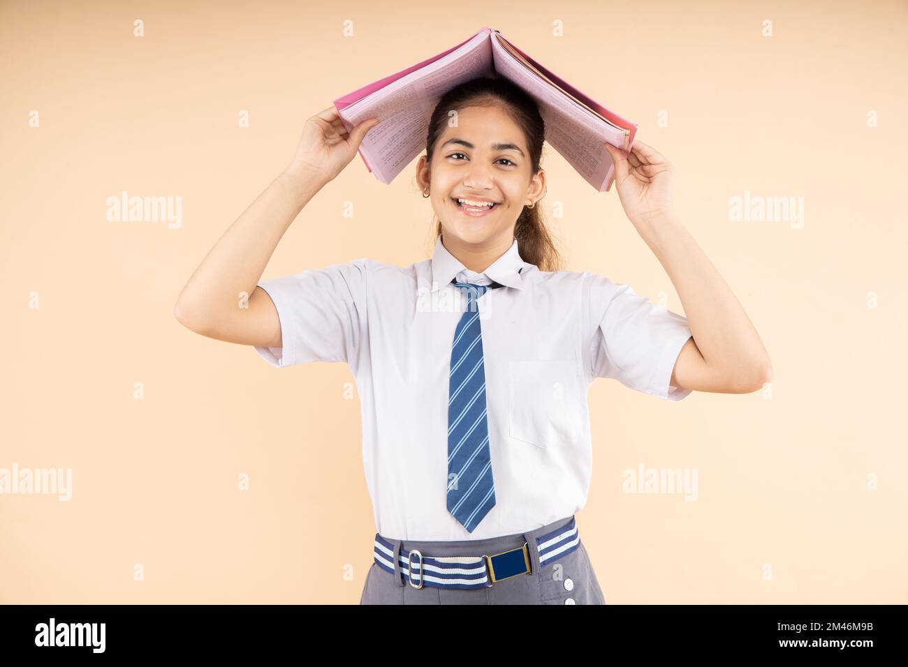 Happy Indian student schoolgirl wearing school uniform holding books on ...
