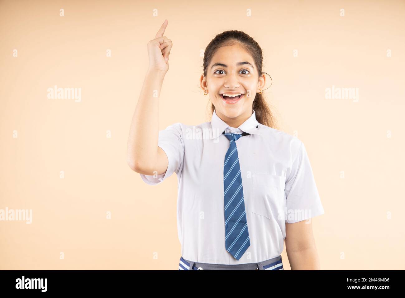 Excited Indian student schoolgirl wearing school uniform having an idea ...
