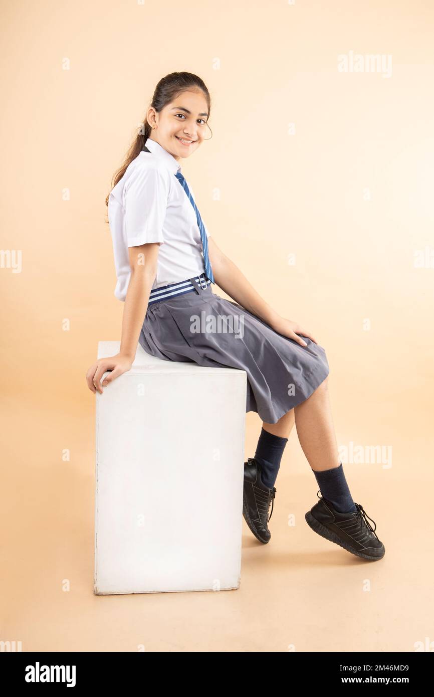 Smiling Indian student schoolgirl wearing school uniform sitting on ...