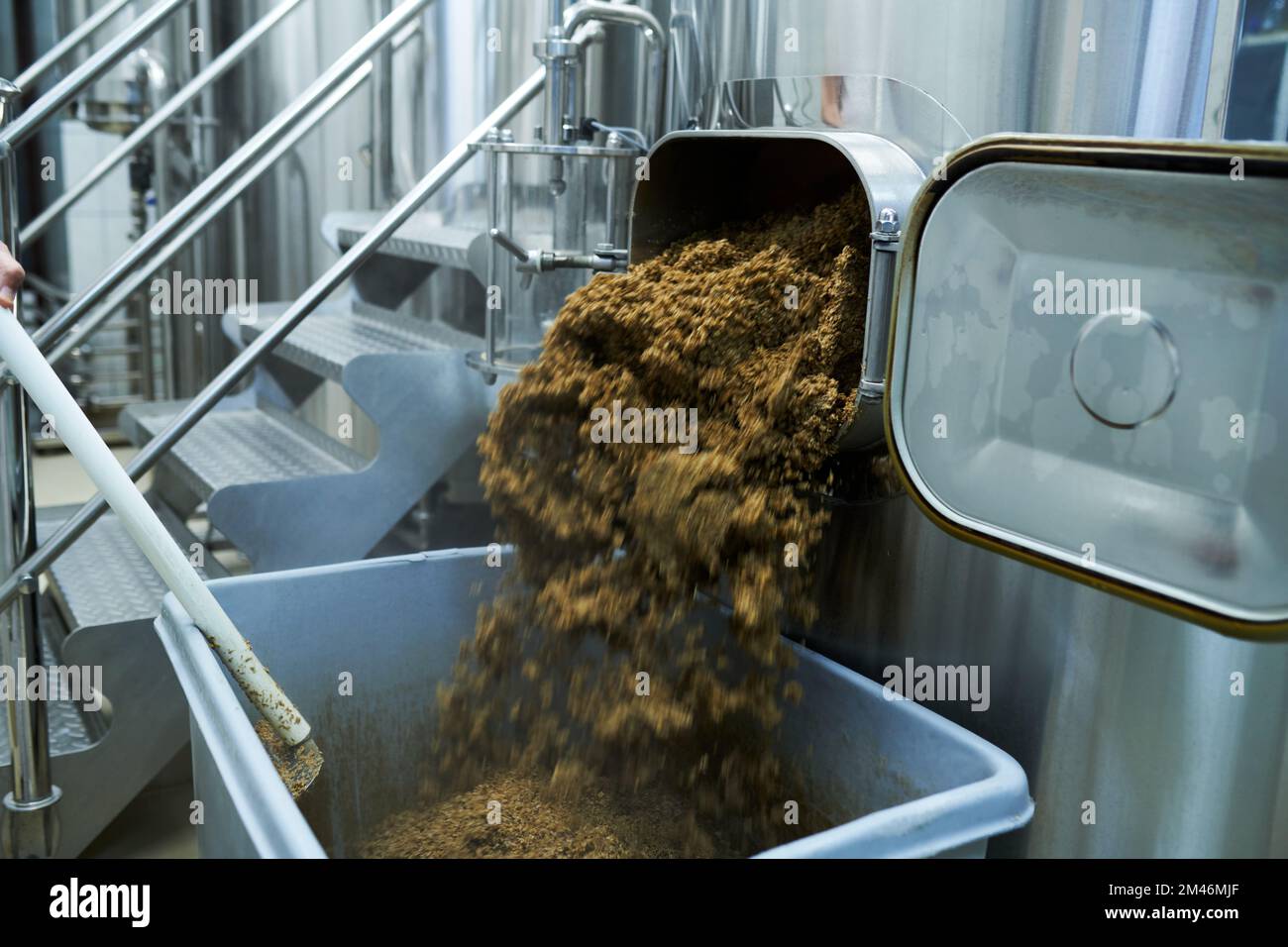 Brewery worker removing spent grain from tank Stock Photo - Alamy