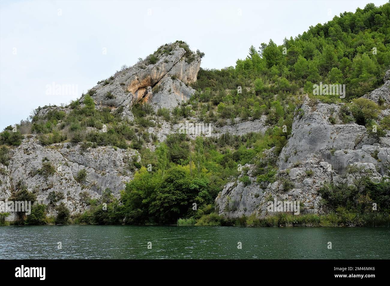 Distance view to the magnificent gray brown cliff rocks with trees and ...