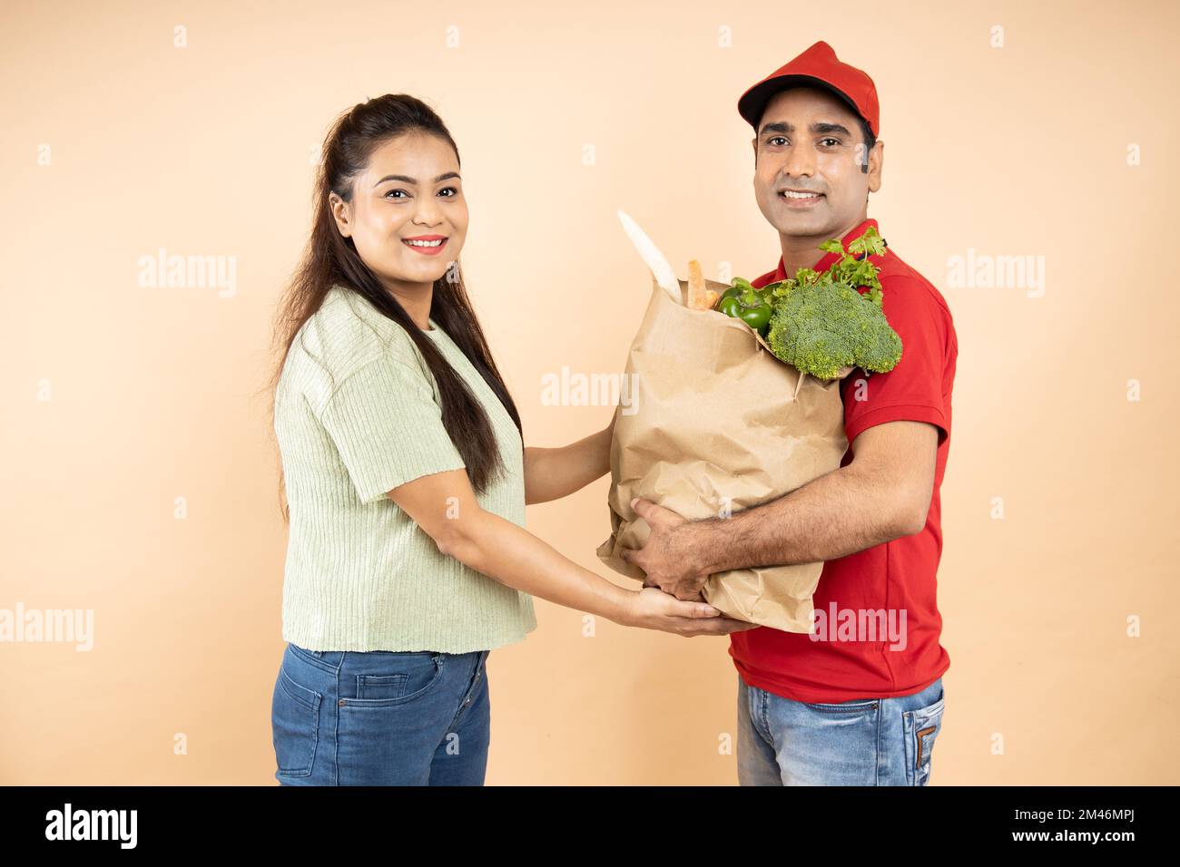 Portrait Indian delivery man wearing red uniform give bag of vegetable ...