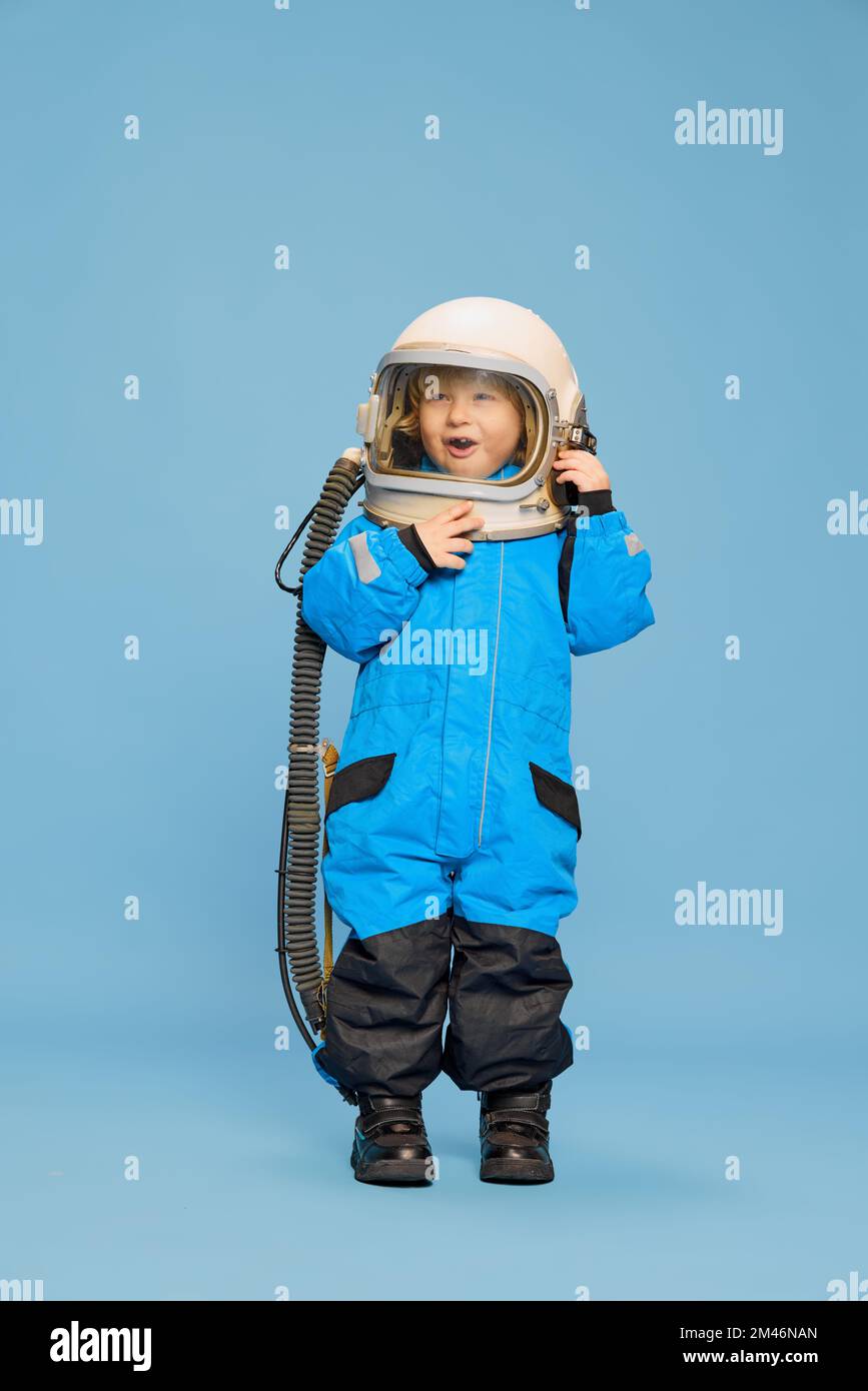 Portrait of little boy, child posing in astronaut costume over blue ...