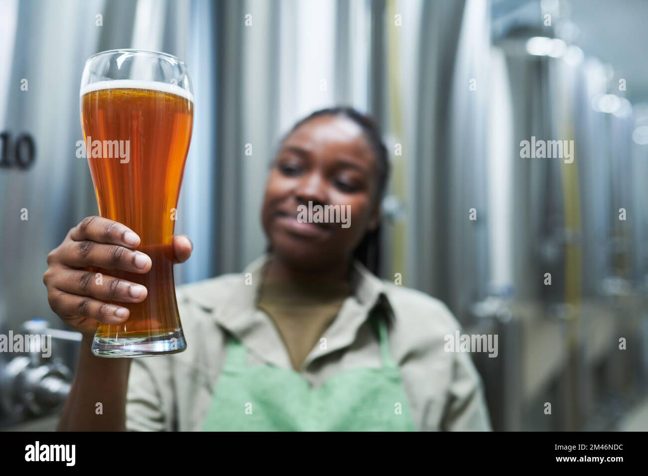 Worker holding big glass of beer produced in small brewery Stock Photo ...