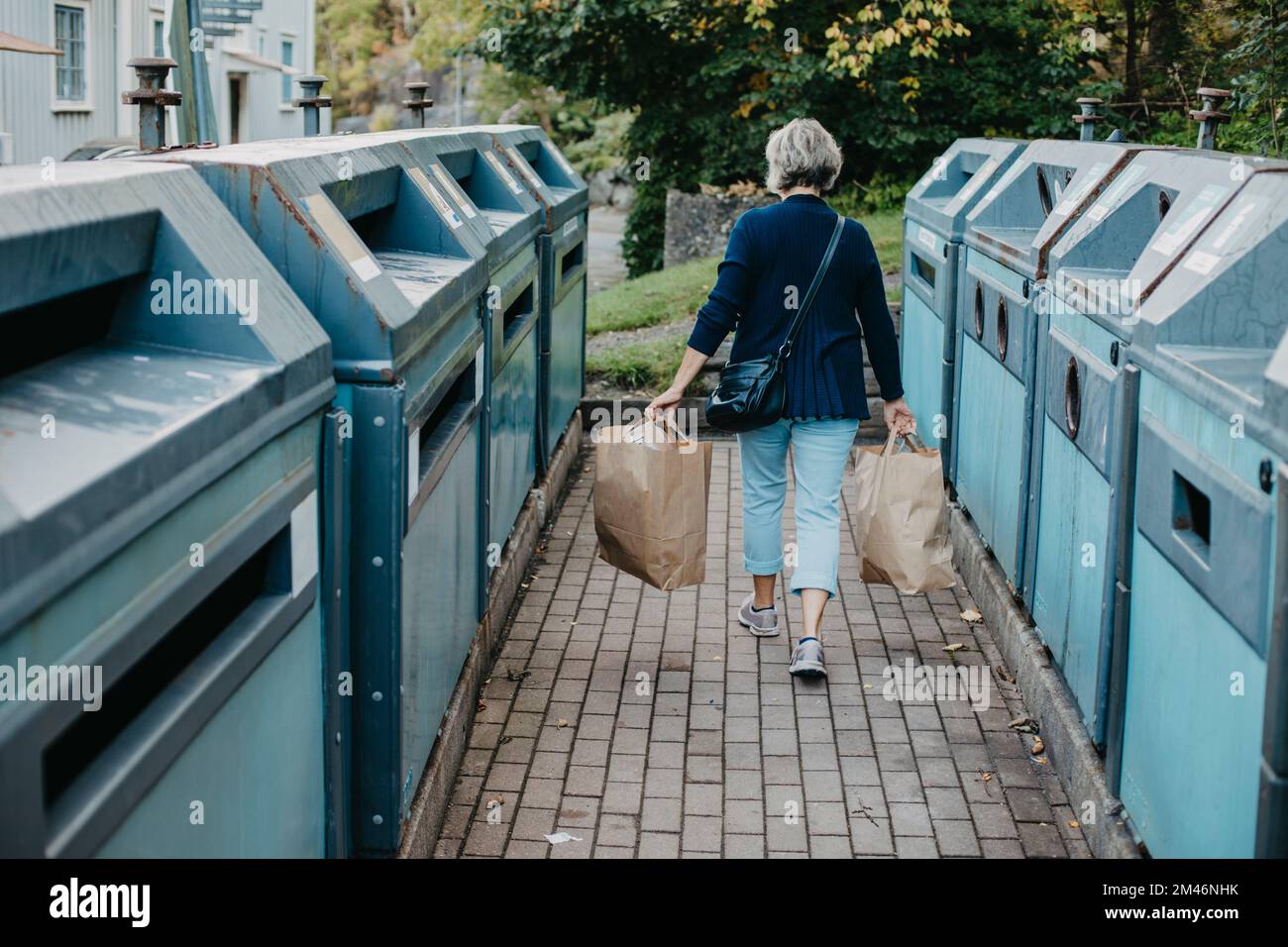 Rear view of woman carrying paper bags with recycling Stock Photo - Alamy
