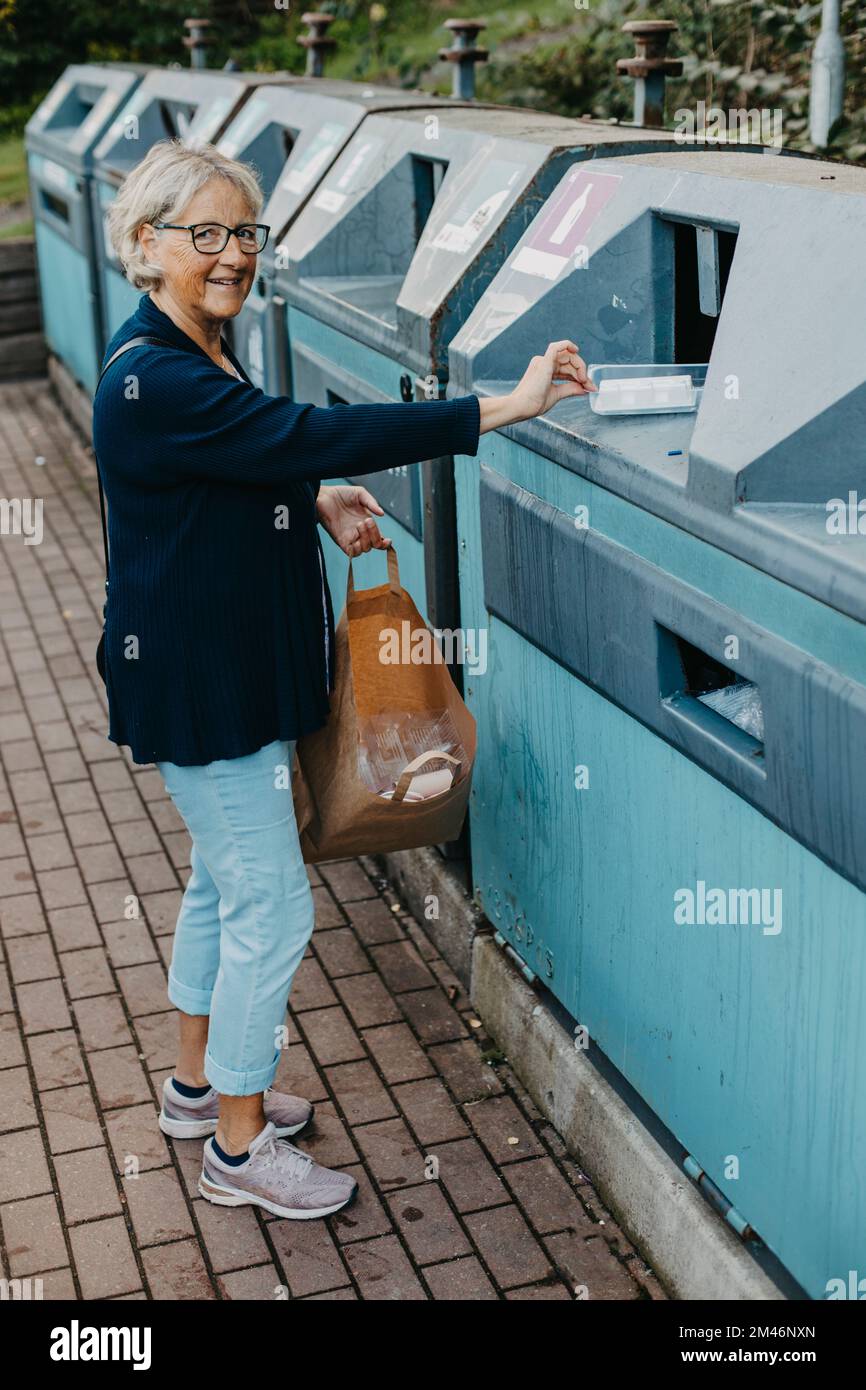 Woman putting plastic in recycling bin Stock Photo - Alamy