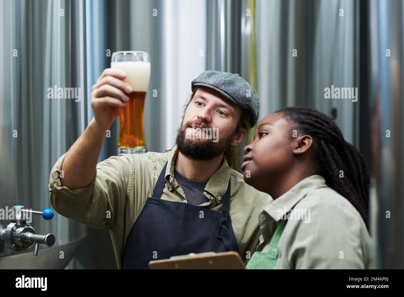 Smiling brewery workers checking thickness of beer froth Stock Photo ...