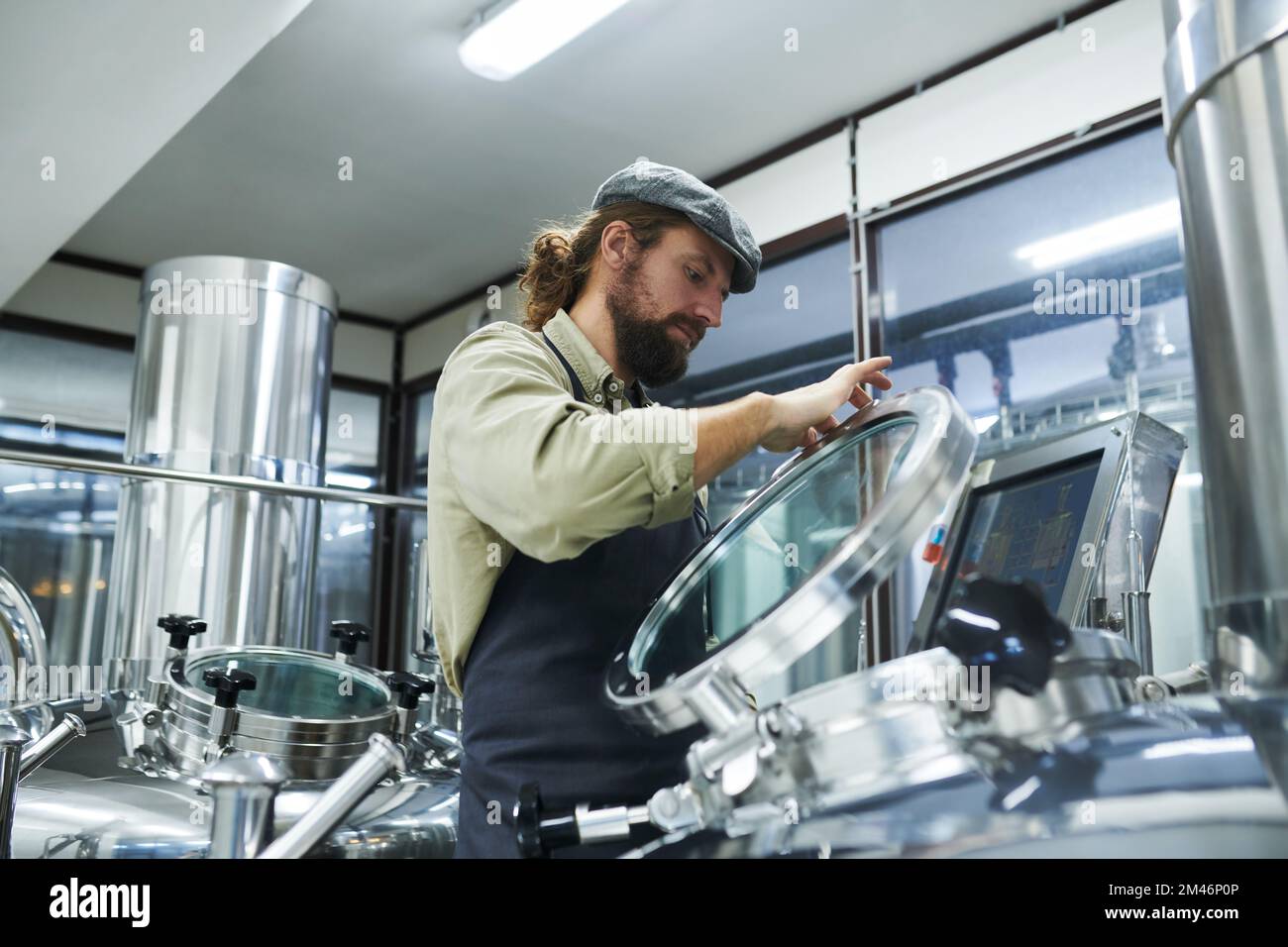 Brewery worker opening tank with fermenting beer to check if process ...