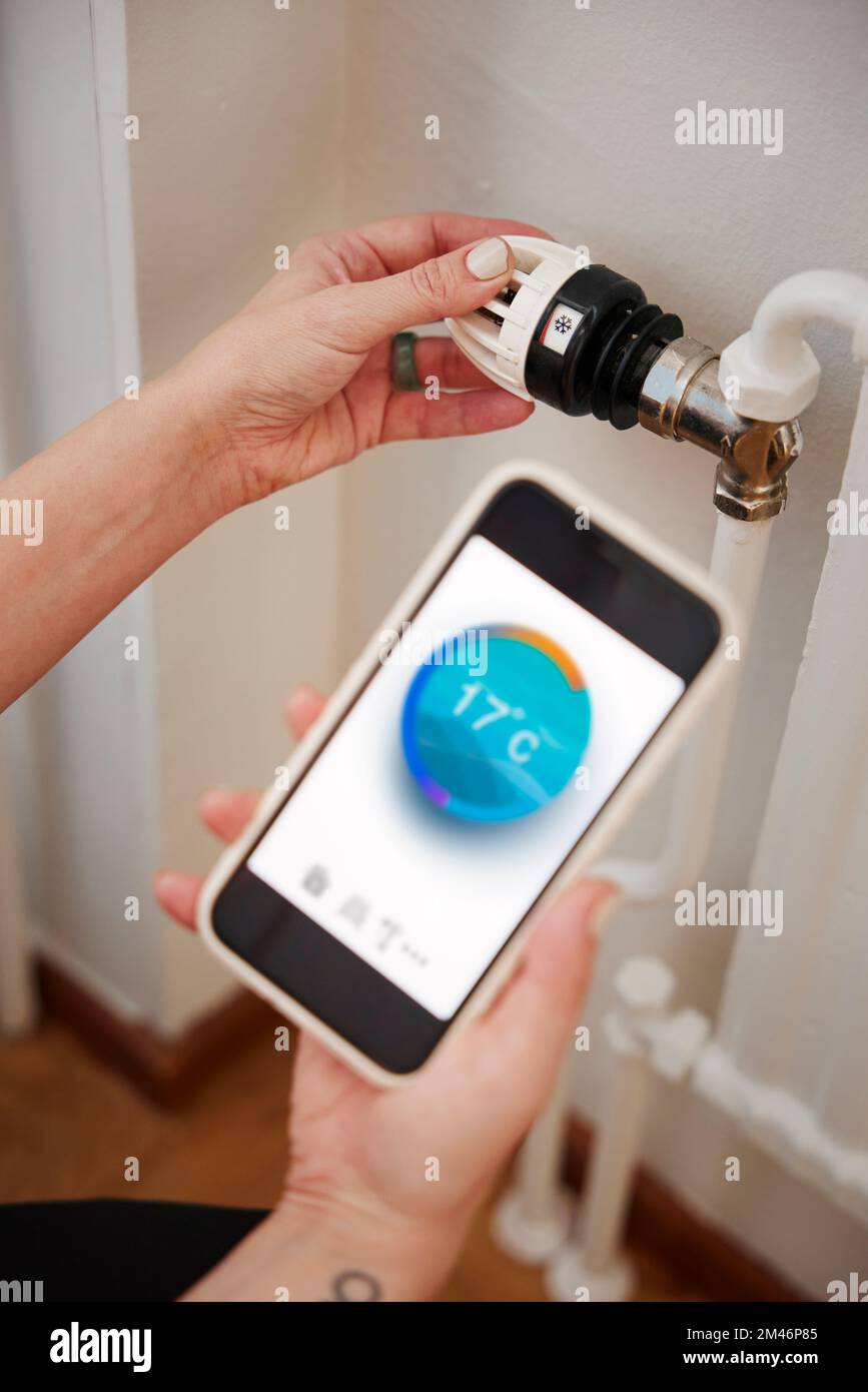 Woman using thermostat and app on phone Stock Photo - Alamy