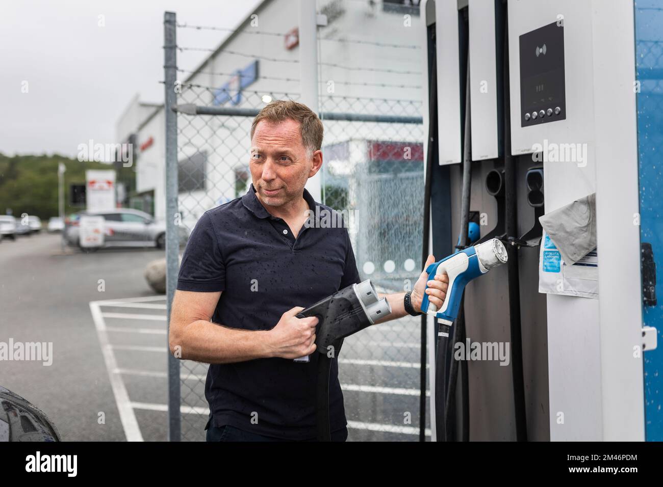 Man charging electric car Stock Photo - Alamy