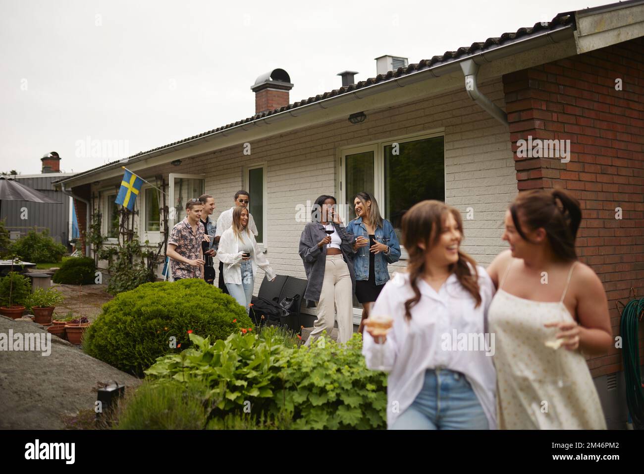 Happy friends in front of house Stock Photo - Alamy