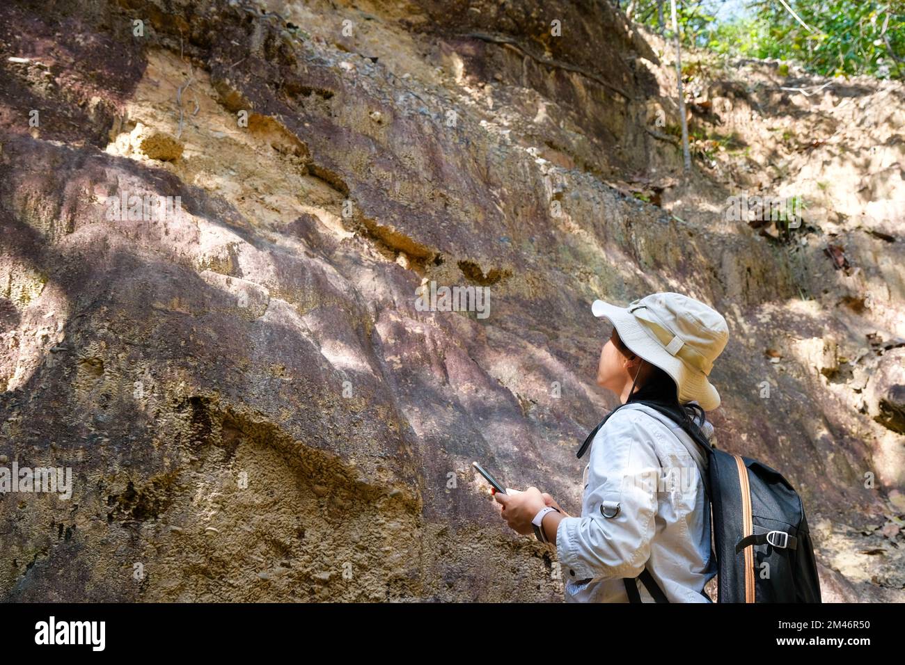 Female geologist with backpack exploring nature trail in forest and ...