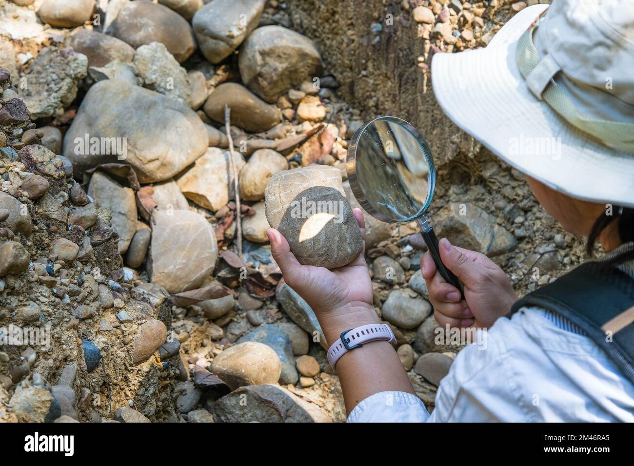 Female geologist using a magnifying glass examines nature, analyzing ...