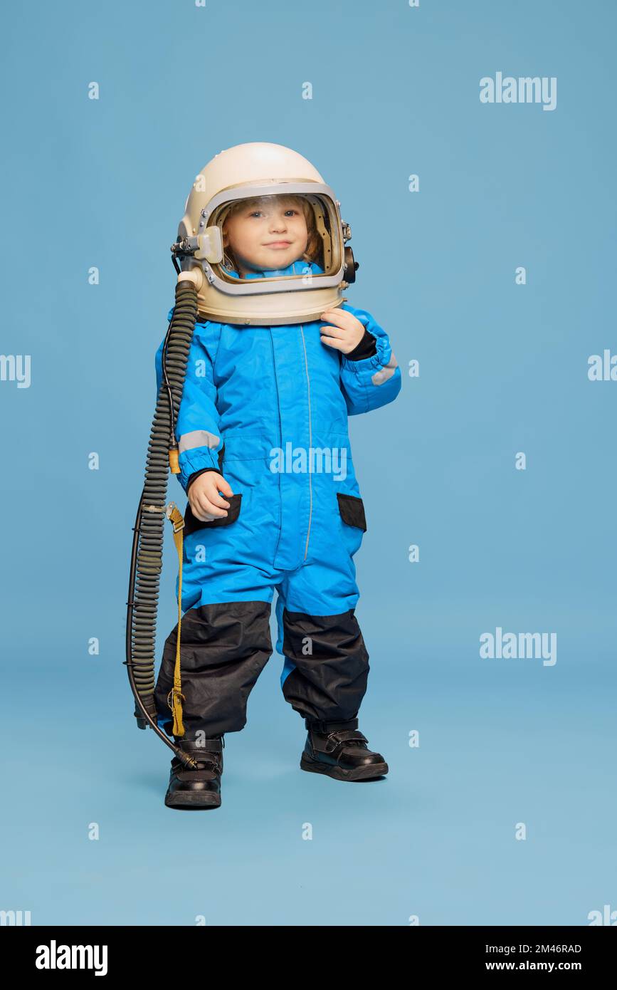 Portrait of little boy, child posing in astronaut costume over blue ...
