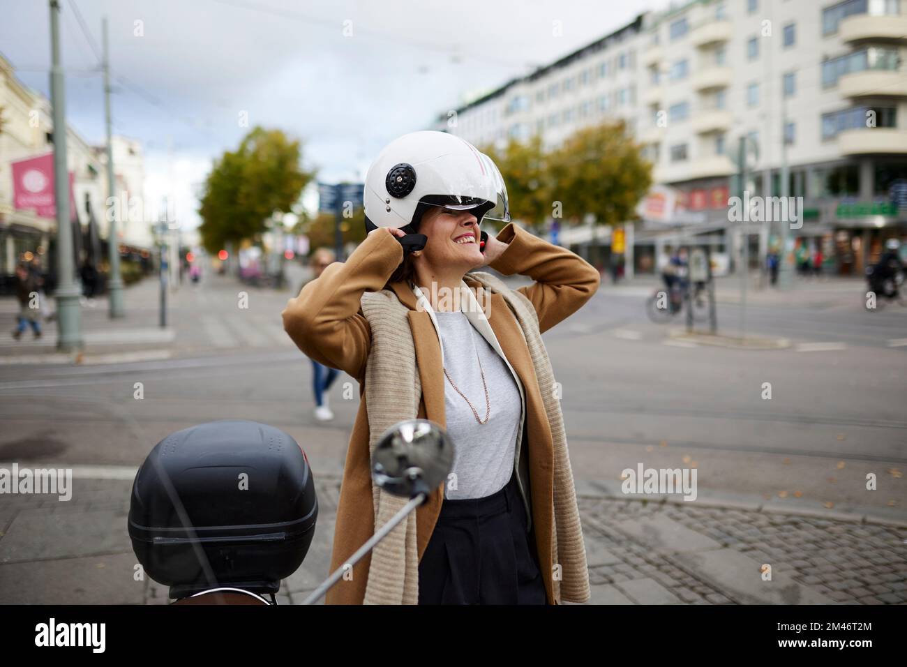 Woman putting on motorcycle helmet Stock Photo - Alamy
