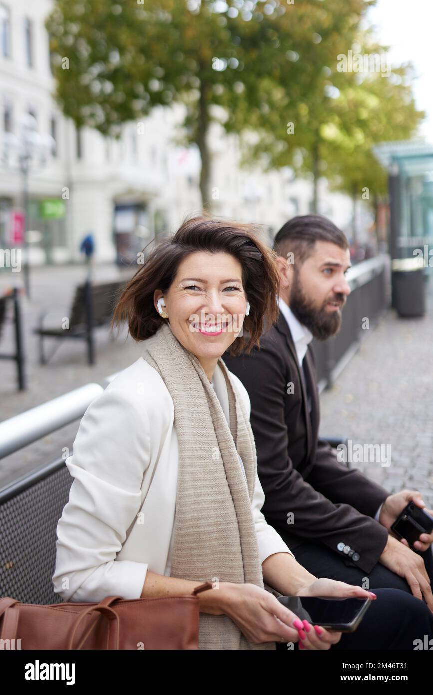 Smiling colleagues sitting on bench Stock Photo - Alamy