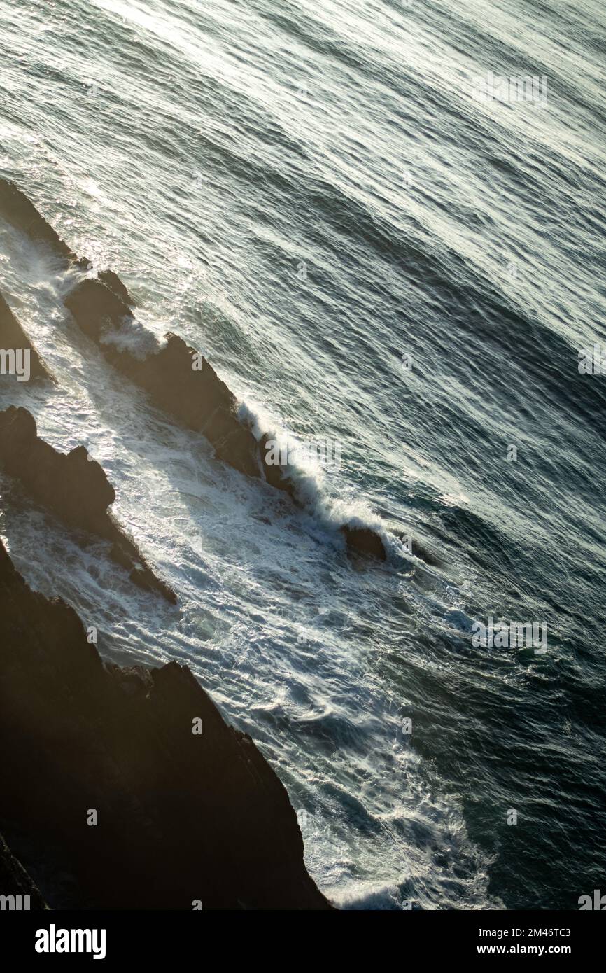 A vertical shot of Praia do Caneiro bordered by cliffs and a resort for ...