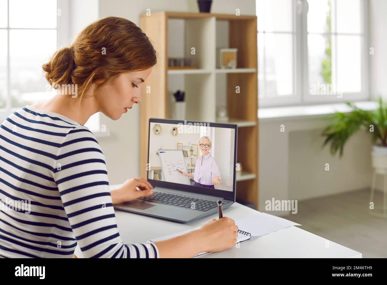 Young woman taking notes during webinar or online class with remote ...