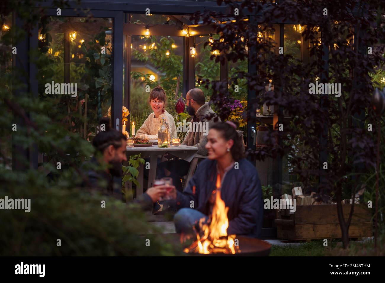 Friends sitting at fire in garden Stock Photo - Alamy