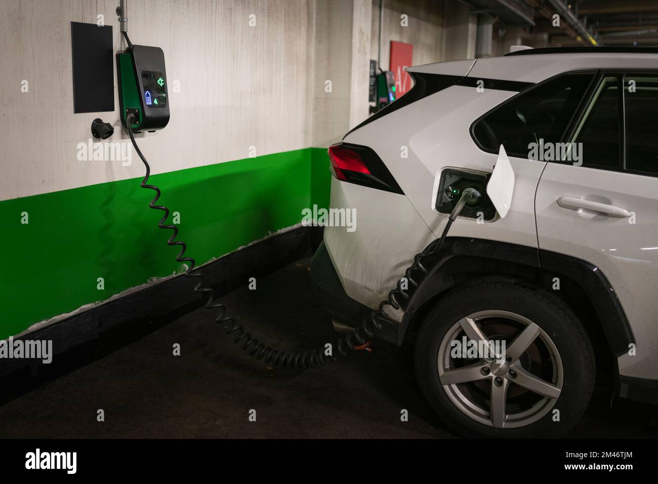 Electric car getting charged in garage Stock Photo - Alamy