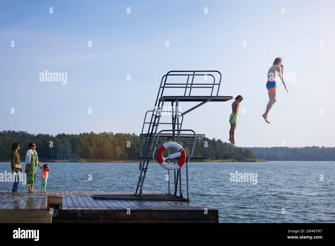 Teenage boys jumping into water from jumping tower Stock Photo - Alamy