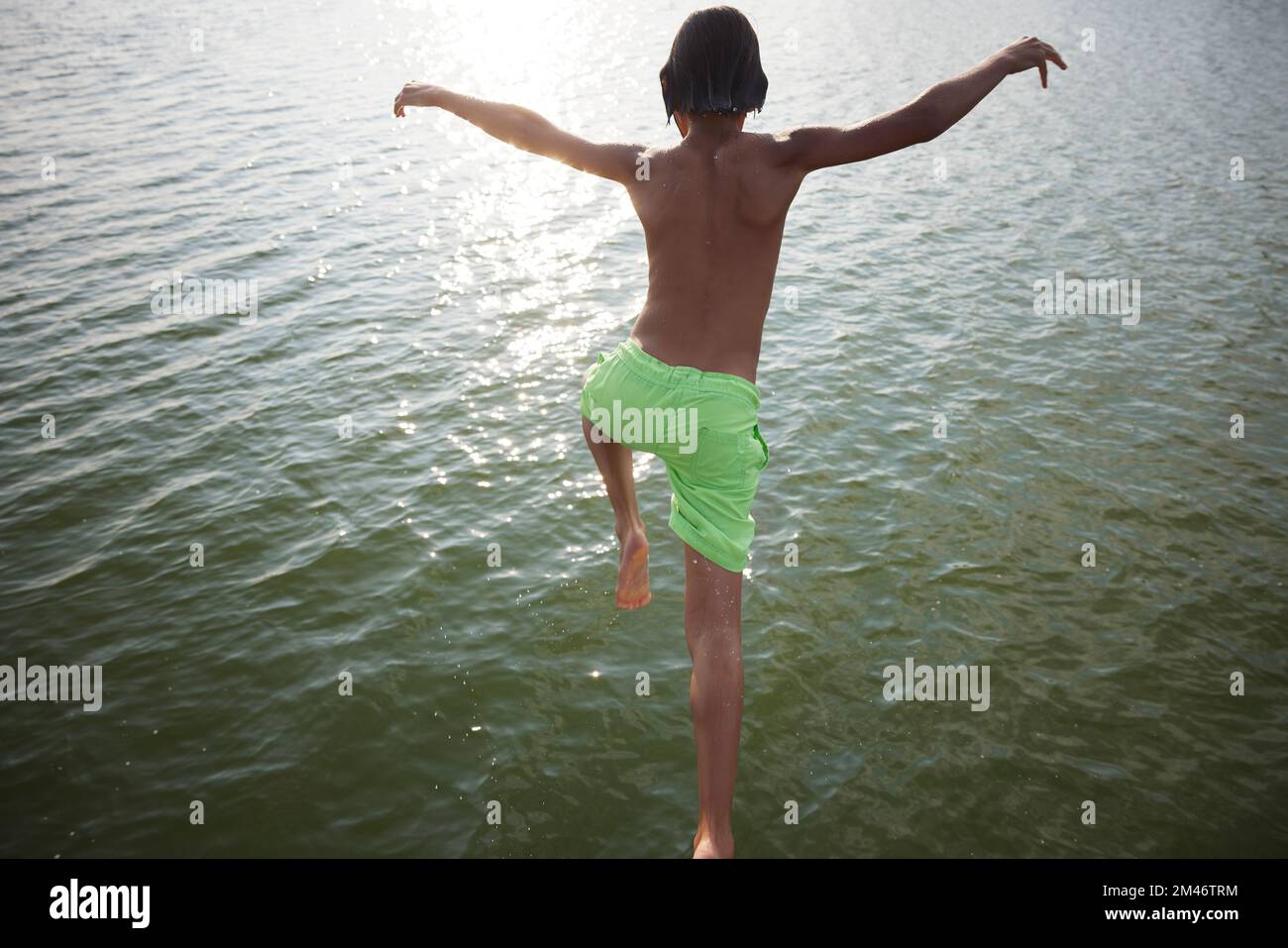 Teenage boy jumping into water Stock Photo - Alamy