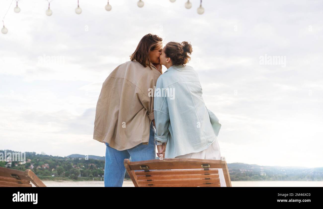 Two women lesbians, lgbt couple gently kissing while relaxing on the ...
