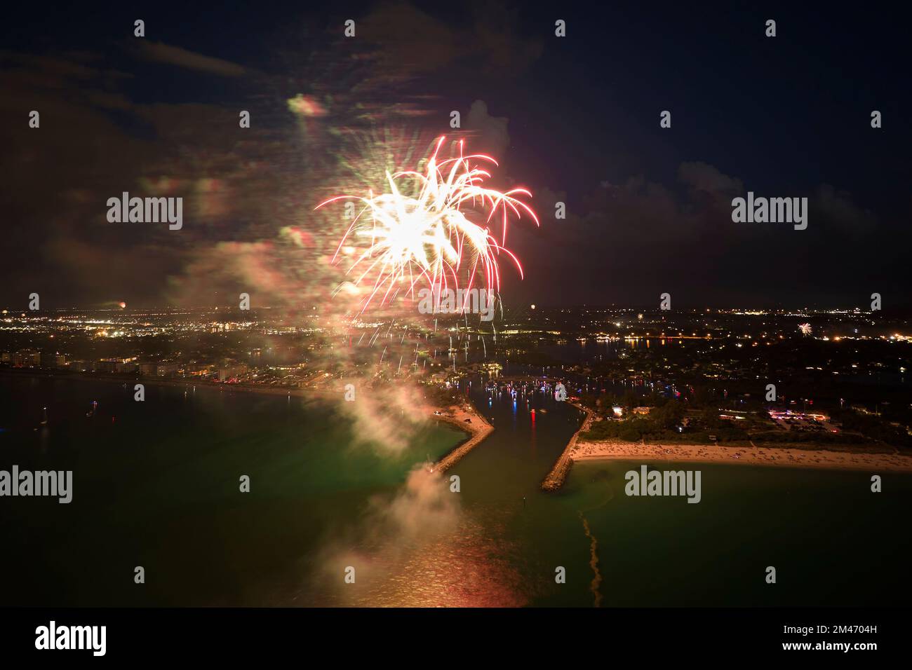 Aerial view of bright fireworks exploding with colorful lights over sea ...