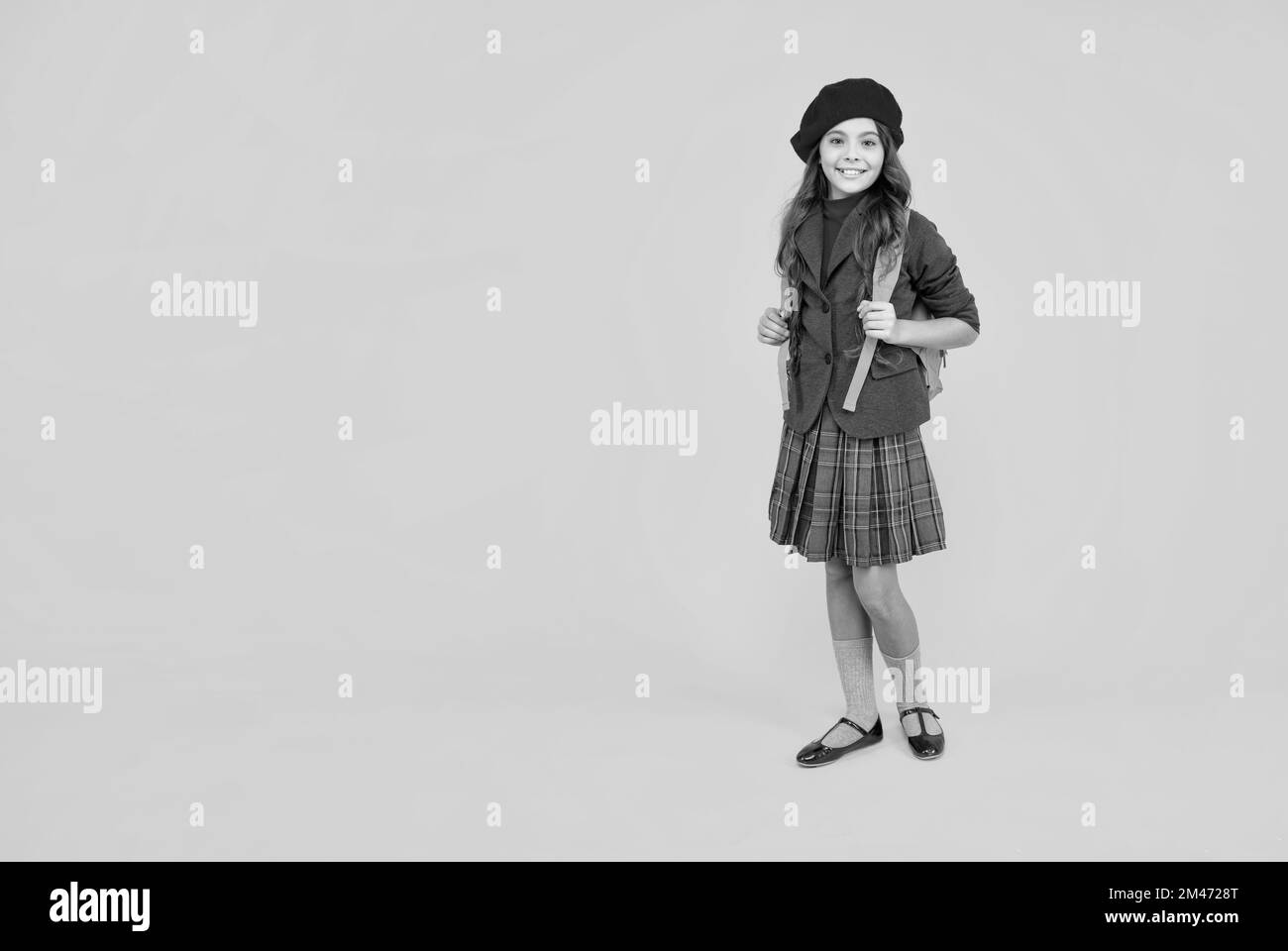 cheerful teen girl in uniform and beret with school bag on yellow ...