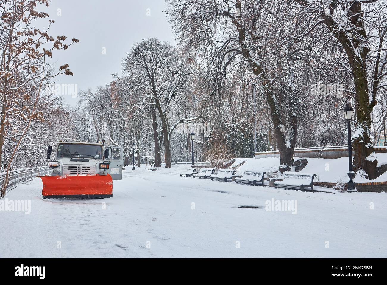 Snow removal tractor cleans alley in park. Tractor removing snow ...