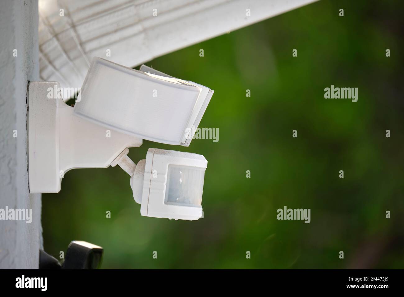Motion sensor with light detector mounted on exterior wall of private ...