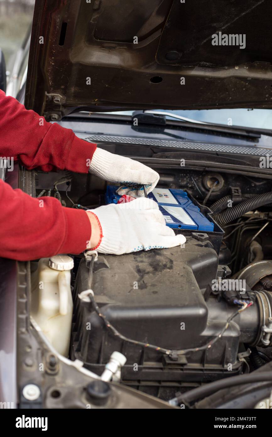 the mechanic fixes the car battery with a wrench. battery replacement ...