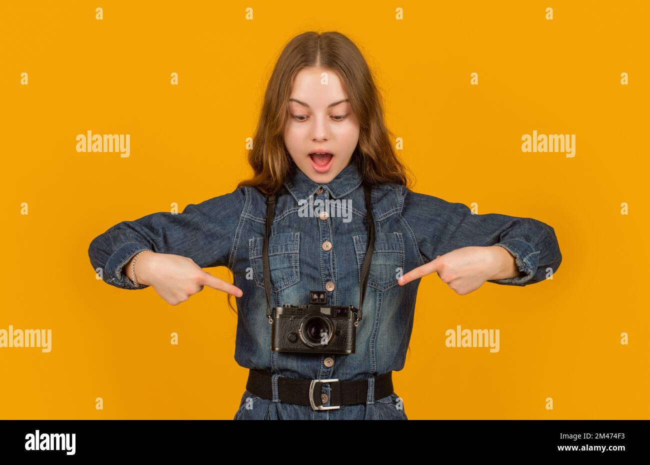 Surprised girl photographer pointing fingers at camera hanging on neck ...