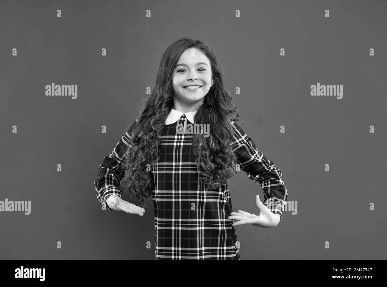happy child with long curly hair presenting product on red background ...