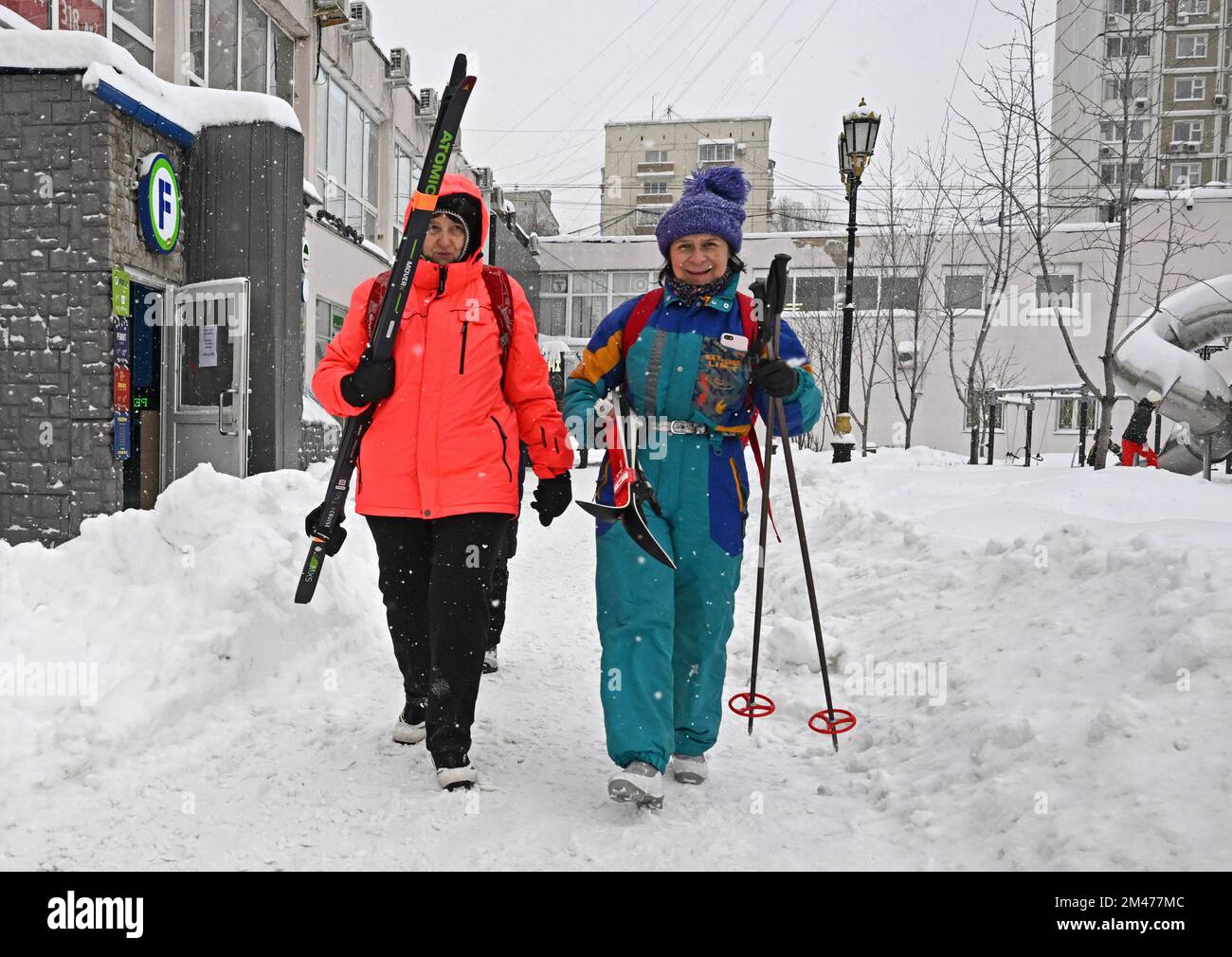 Genre photography. Snowfall in the city. Two women with skis are ...
