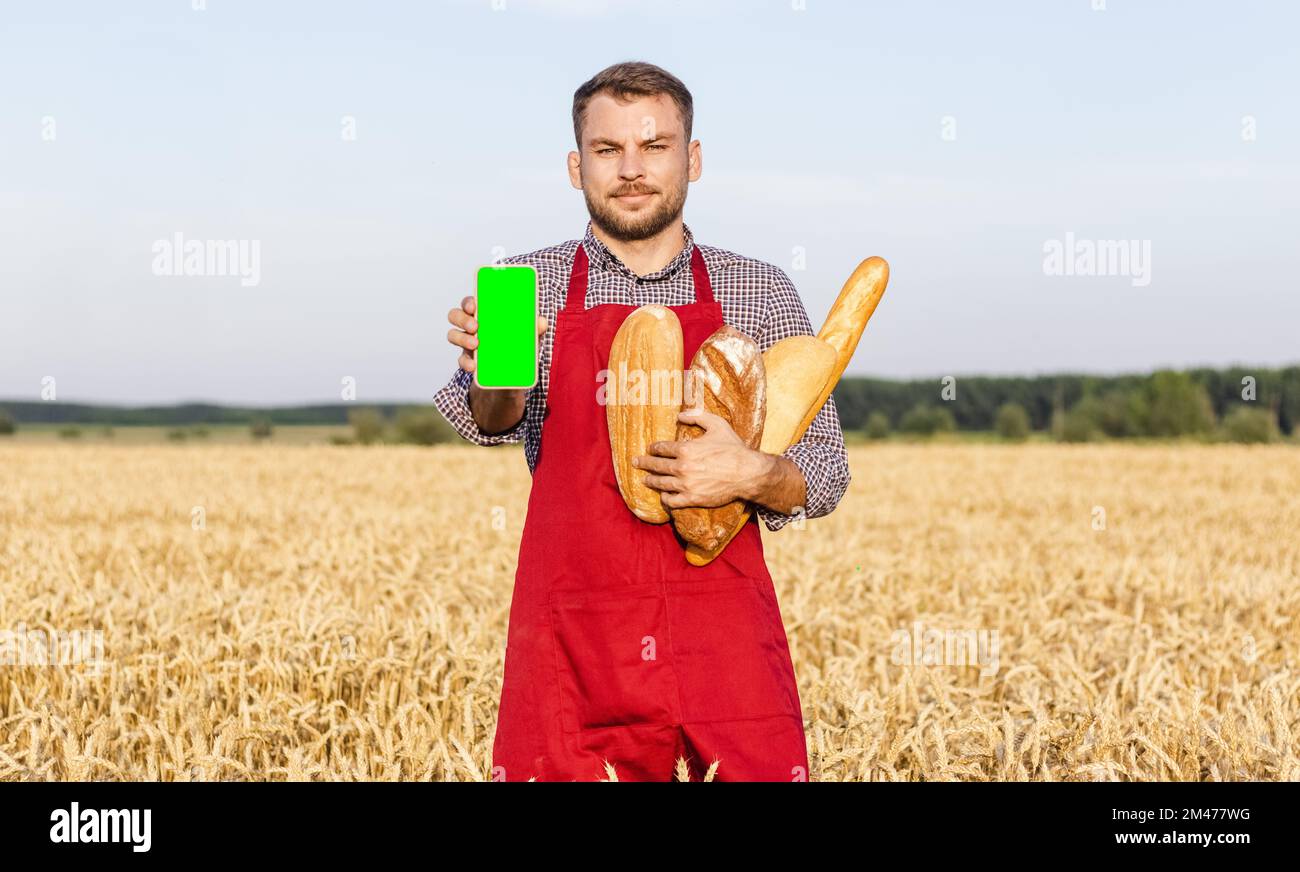 Baker man holding loaves of bread in his hand and showing the screen of ...