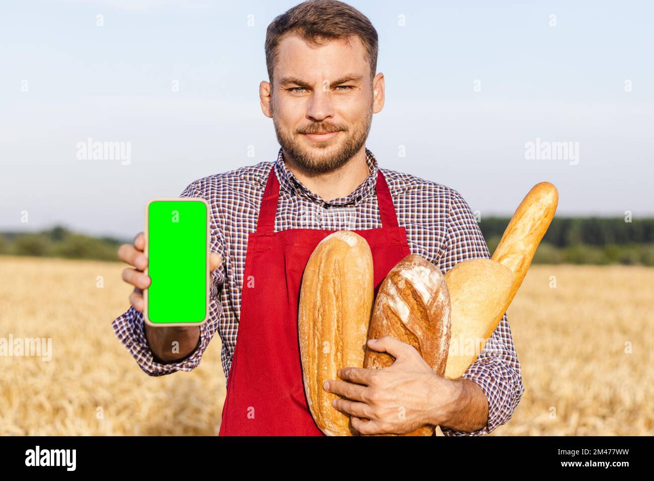 Baker man holding loaves of bread in his hand and showing the screen of ...