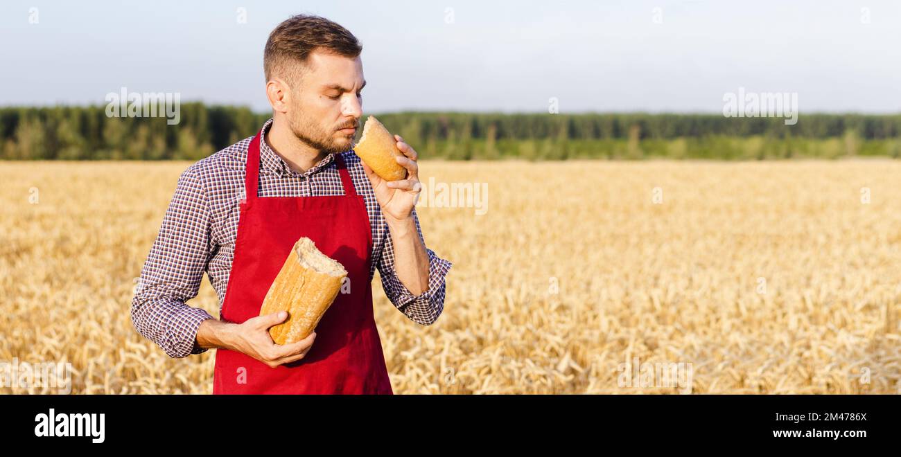 Man in apron standing in wheat field and smelling fresh bread Stock ...